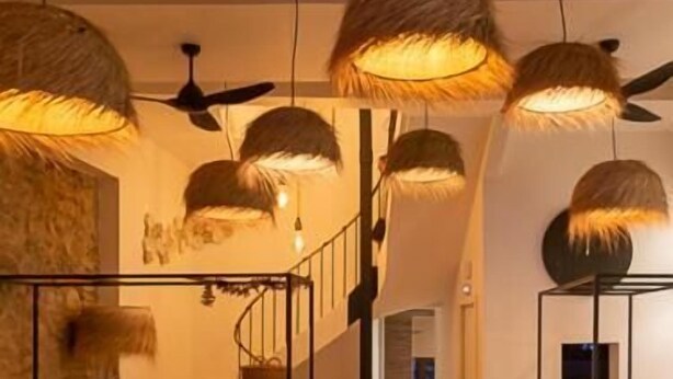 Um interior moderno com escada, luminárias pendentes e um espaço de jantar.