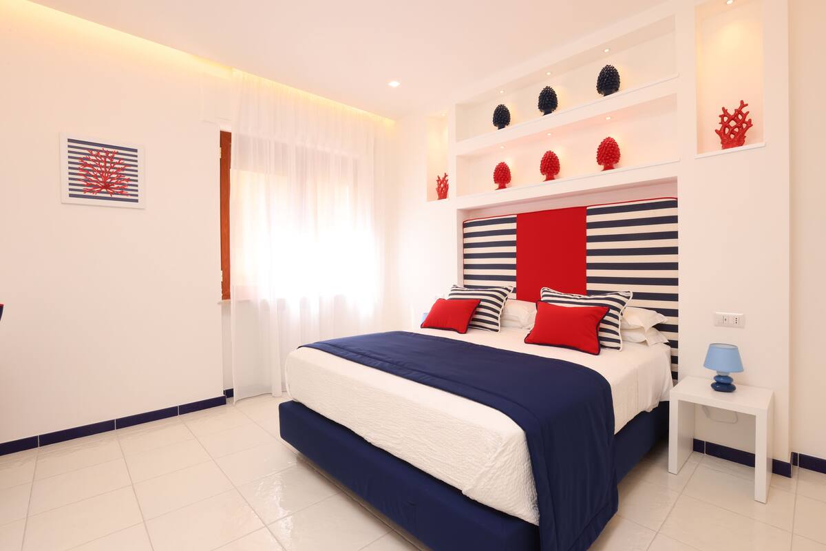 Um quarto moderno com uma cama grande, cabeceira listrada e prateleiras decorativas na parede.