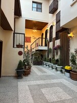 Pátio com escadaria central, vasos de plantas e piso de azulejos.