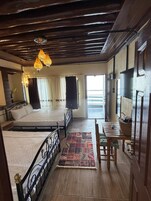Quarto com duas camas, área de refeições e vista através de uma grande janela.