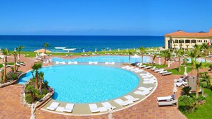 Um resort com uma piscina grande, espreguiçadeiras e vista para o oceano.