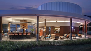 Um edifício moderno com estrutura circular, área de bar e disposição de assentos.