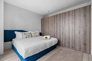 Um quarto moderno com cama, cabeceira azul e parede de destaque em madeira.