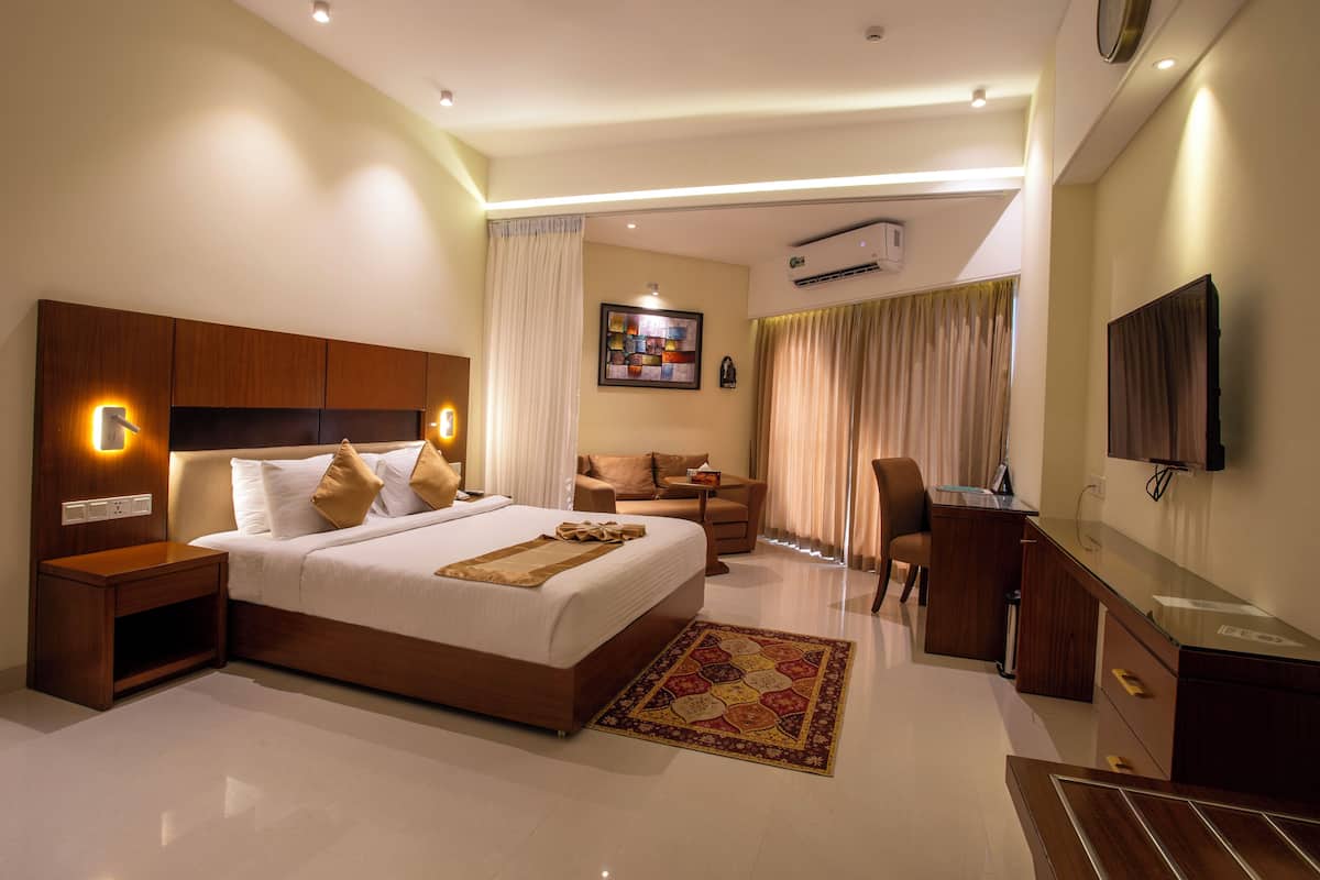 Quarto de hotel moderno com uma cama grande, uma escrivaninha, uma cadeira e uma televisão.
