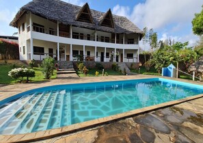 Uma casa de dois andares com piscina na frente.