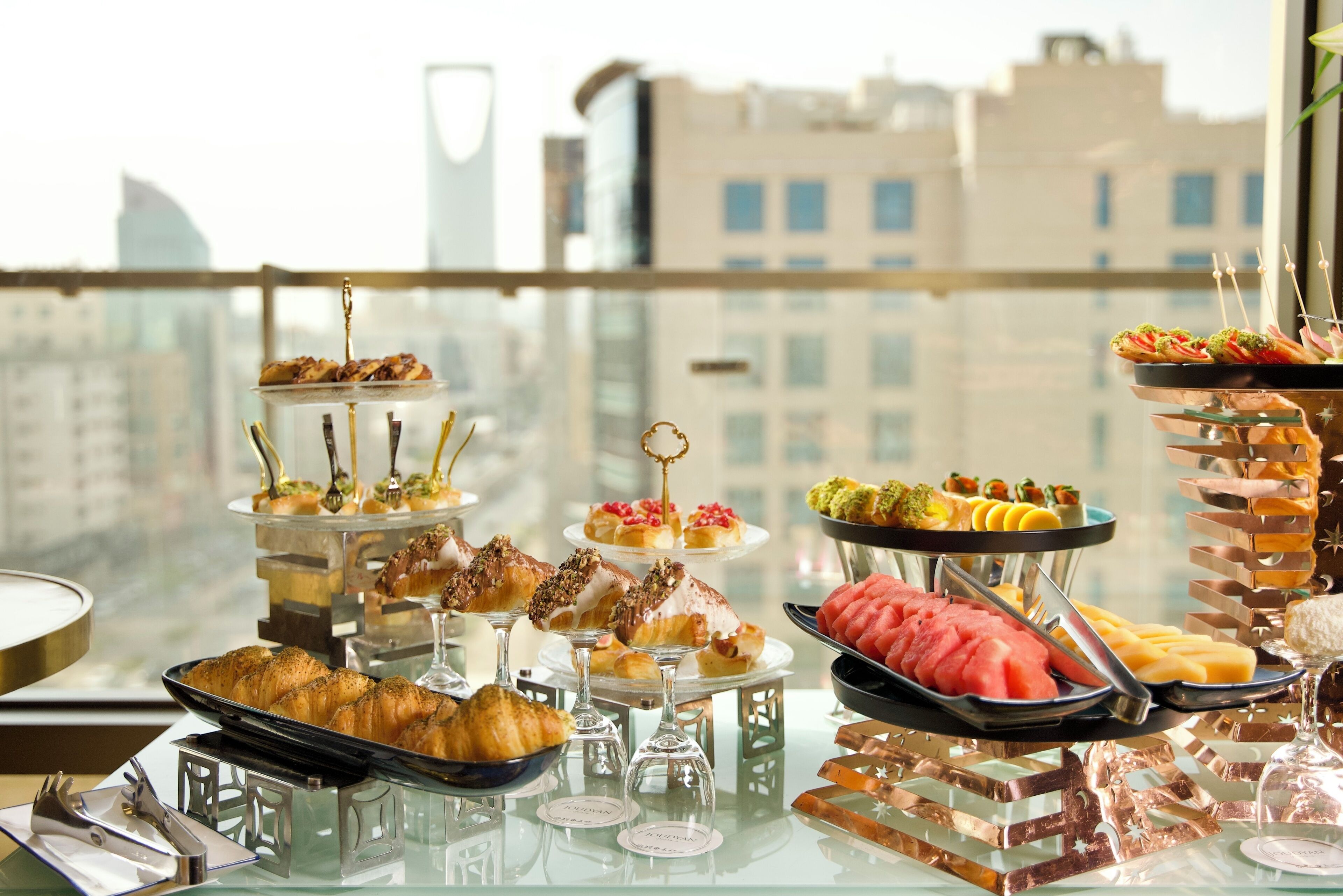 Buffet variado com diversos alimentos e vista para a cidade ao fundo.