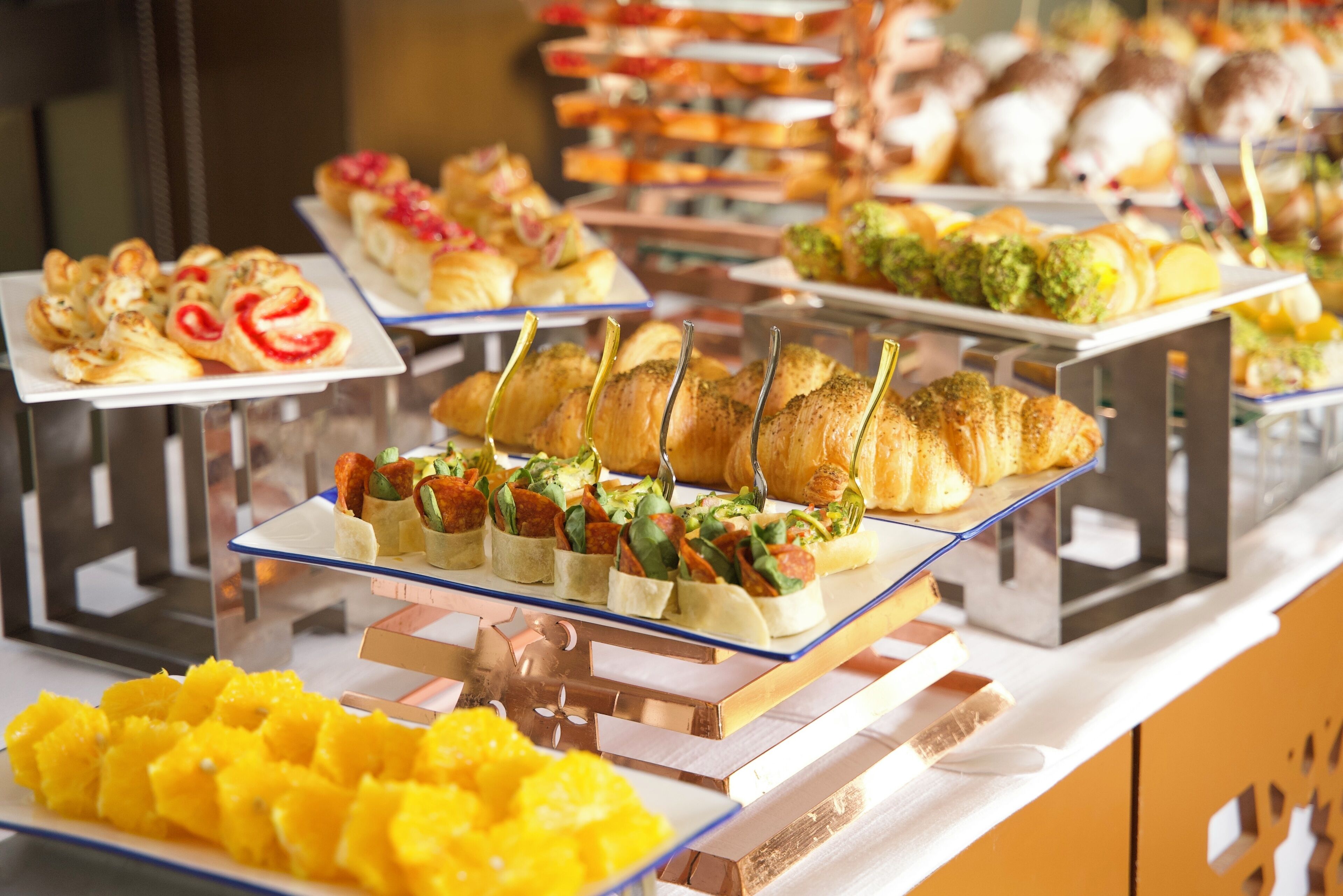 Buffet com diversos alimentos, incluindo doces, sanduíches e frutas.