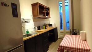Cozinha compacta com bancada de madeira, pia e pequena mesa de jantar com toalha xadrez.