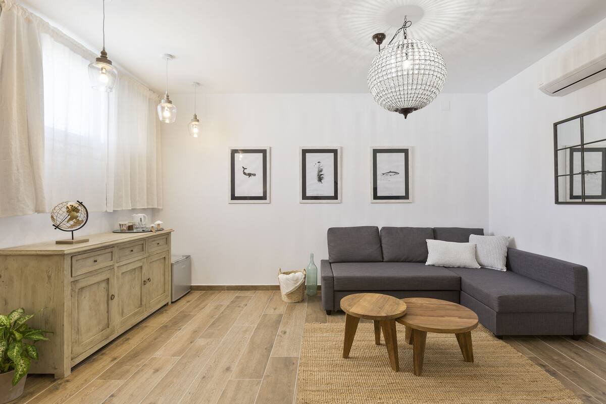 Uma sala de estar moderna com um sofá cinzento, mesa de centro de madeira e um globo em um armário.