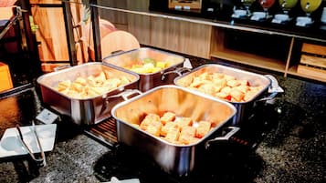 Buffet com diversos alimentos em recipientes de metal.