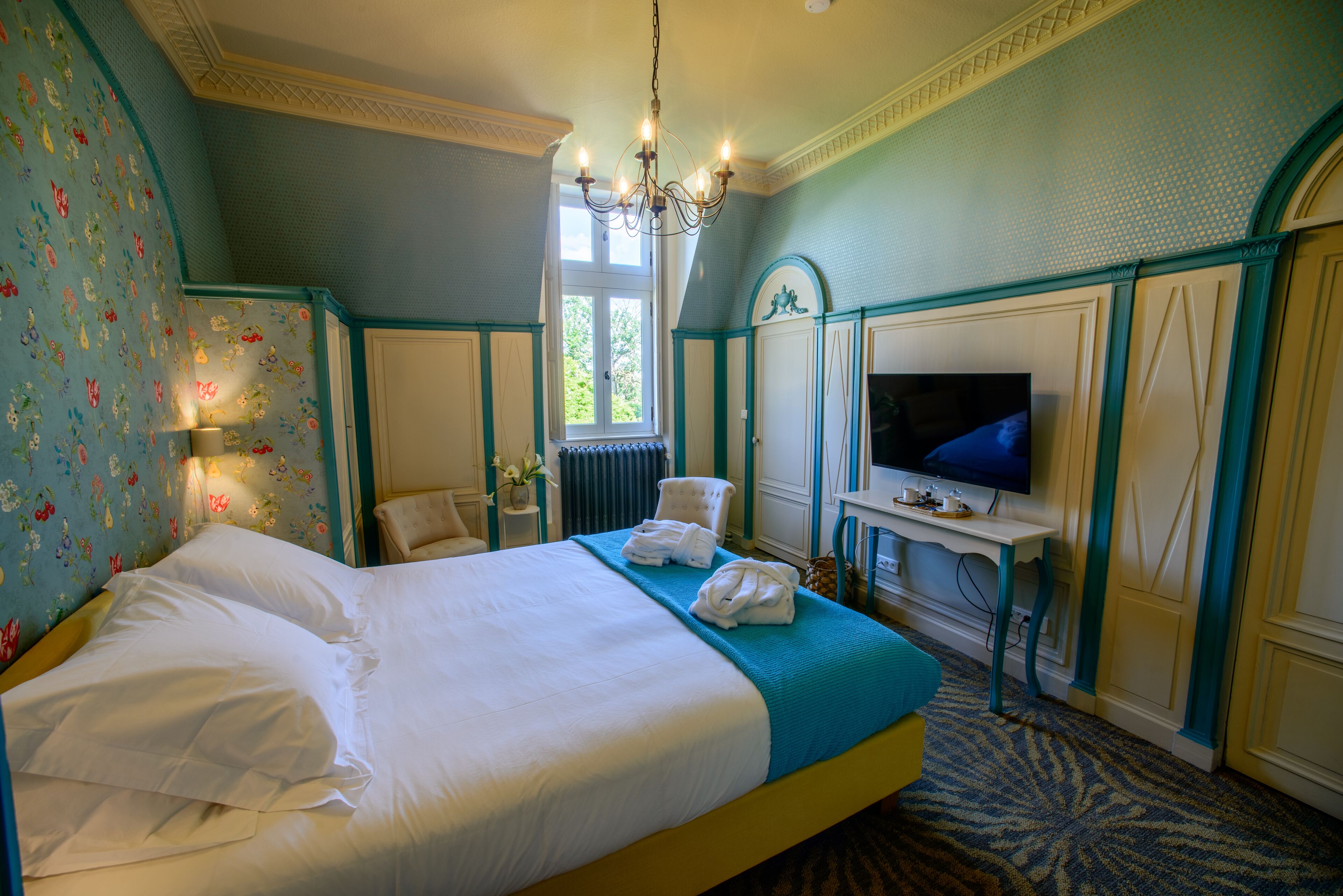 Quarto de hotel com cama, televisão, janela e banheiro.