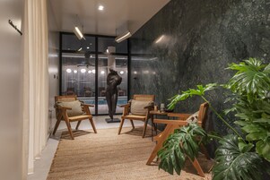 Um interior moderno com parede de mármore escuro, mobiliário de madeira e uma planta grande.