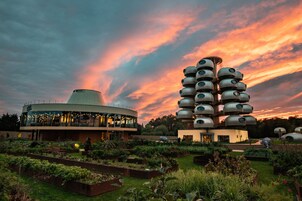 Um edifício moderno com estrutura circular e uma série de torres cilíndricas.