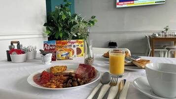 Uma mesa de café da manhã com um prato de feijão, torradas e um copo de suco de laranja.