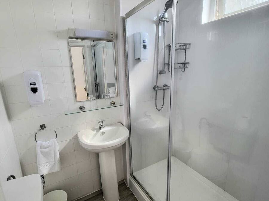 Casa de banho moderna com cabine de duche em vidro, lavatório, sanita e espelho.