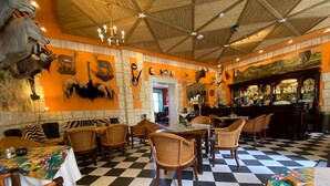 Um restaurante com chão xadrez, cadeiras de vime e mesas com toalhas de mesa floridas.