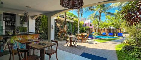 Restaurante com área externa, piscina e vegetação exuberante.