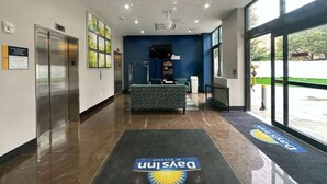 Um lobby moderno com balcão de recepção, área de estar e uma grande janela com vista para o exterior.
