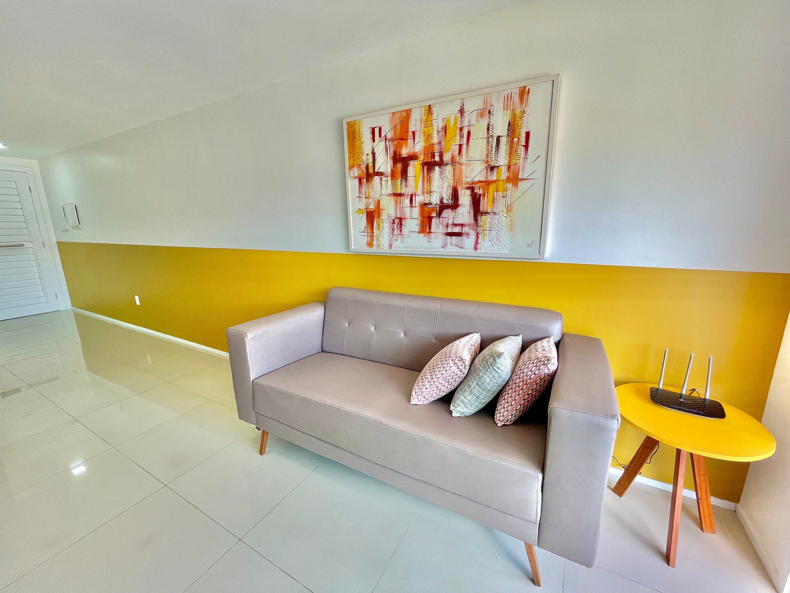 Uma sala de estar moderna com um sofá, uma mesinha redonda e um quadro abstrato pendurado na parede.