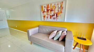 Uma sala de estar moderna com um sofá, uma mesinha redonda e um quadro abstrato pendurado na parede.