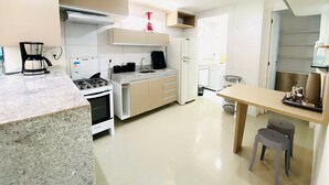 Cozinha moderna com fogão, forno, cafeteira e área de refeições com banquetas.