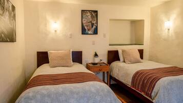 Quarto de hotel com duas camas, uma mesa de cabeceira, um abajur e um quadro na parede.