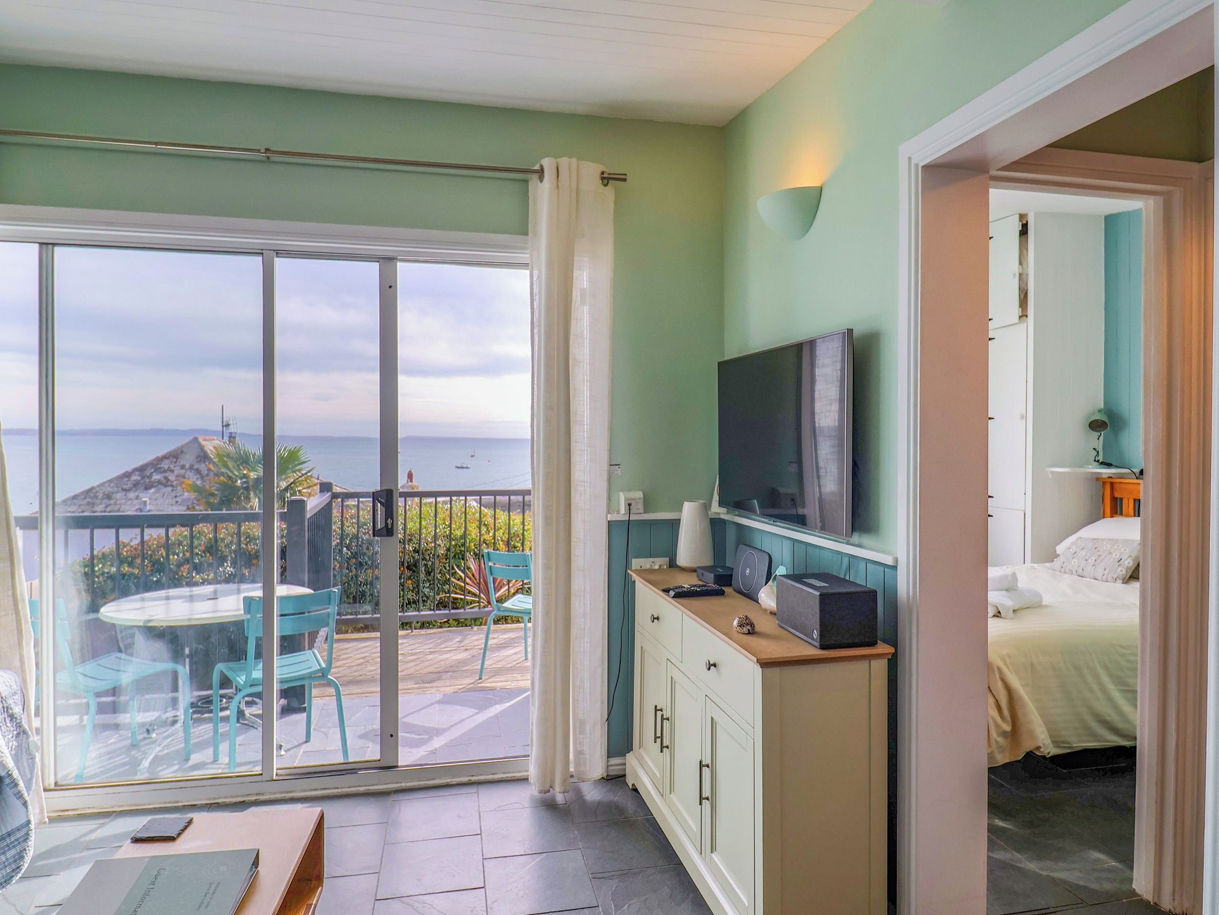 Quarto com porta de vidro deslizante que dá para uma varanda com vista para o mar.