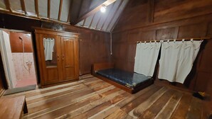 Quarto de madeira com cama em mezzanine, guarda-roupa de madeira e área de chuveiro.