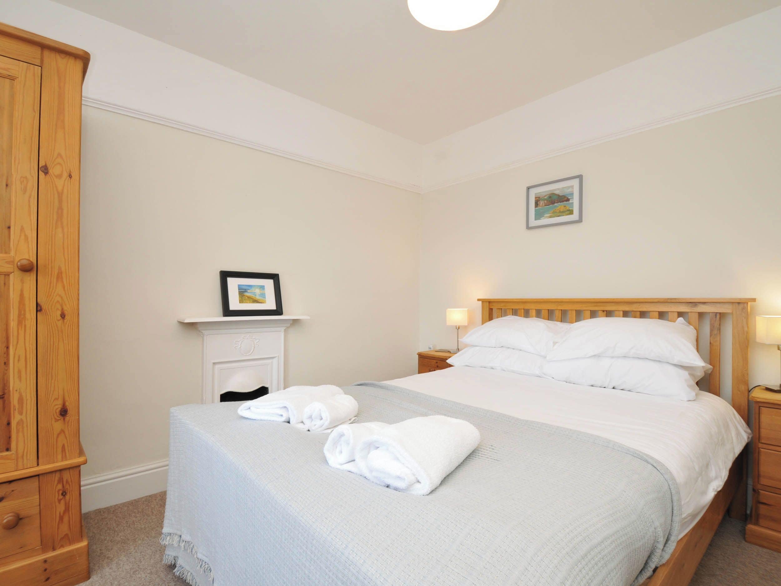 Quarto com cama, guarda-roupa de madeira, lareira e quadro na parede.