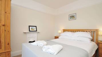 Quarto com cama, guarda-roupa de madeira, lareira e quadro na parede.