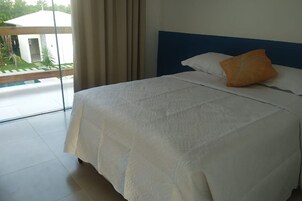 Quarto de hotel com uma cama grande, vista para um jardim e uma varanda.
