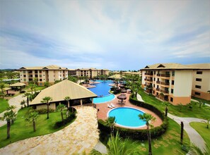 Um resort com várias piscinas, palmeiras e um gramado bem cuidado.