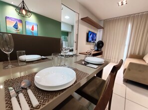 Uma área de jantar com uma mesa posta para dois, incluindo pratos, talheres e copos.