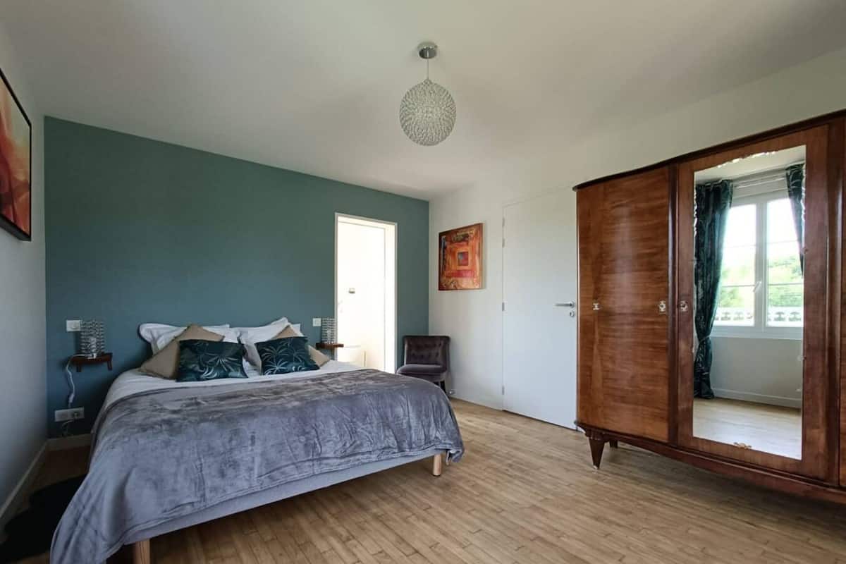 Quarto com cama, guarda-roupa, porta e iluminação no teto.