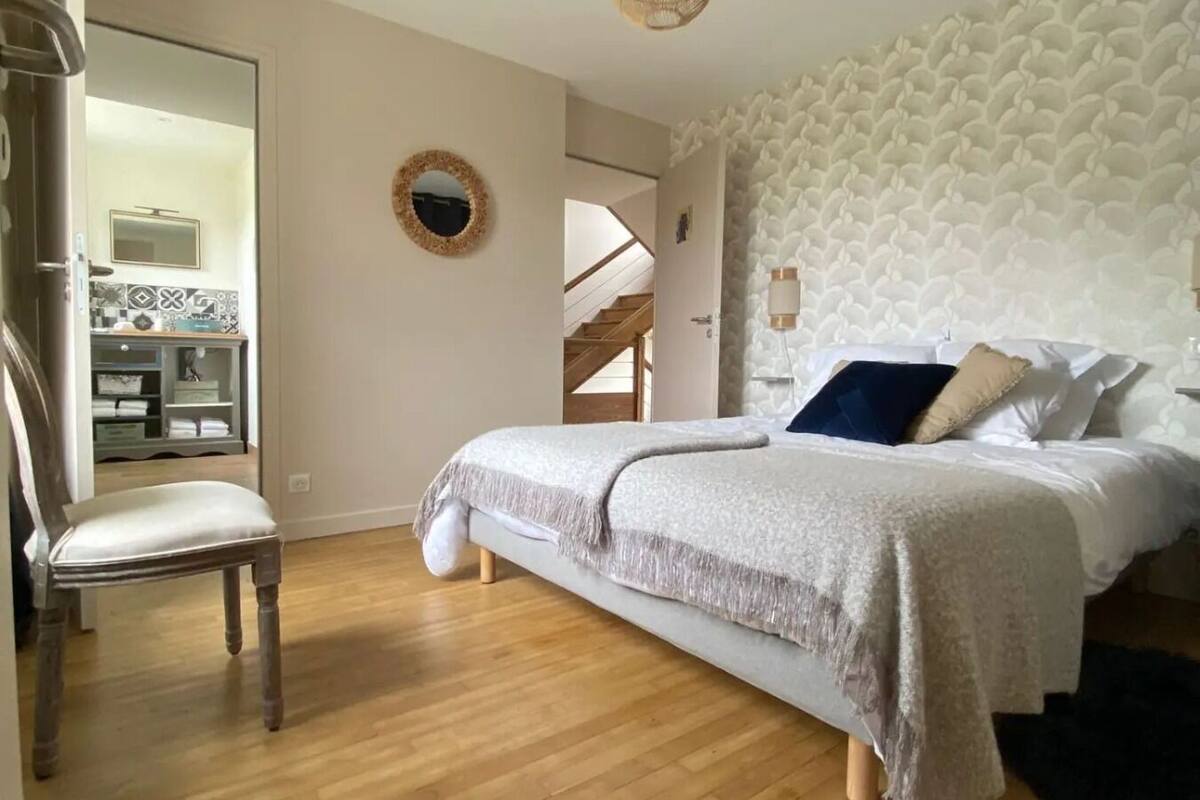Quarto com cama, cadeira, espelho e escada.