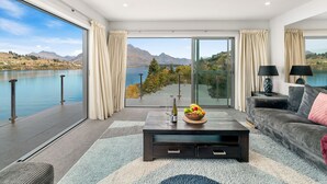 Uma sala de estar moderna com uma grande porta de vidro que dá para uma varanda com vista para o lago.