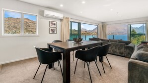 Uma sala de estar moderna com área de jantar, grandes janelas com vista para as montanhas e um ambiente acolhedor para relaxar.
