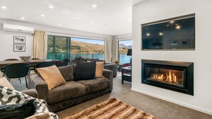 Uma sala de estar moderna com lareira, assentos confortáveis e uma vista panorâmica de um lago.