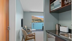 Cozinha moderna com vista para um lago, área de jantar com cadeiras e um micro-ondas na bancada.