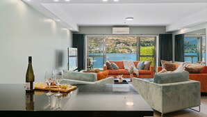 Sala de estar moderna com uma grande janela que oferece uma vista panorâmica de um lago e colinas.