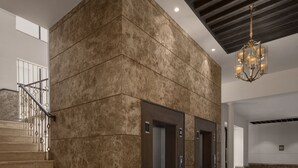 Um hall amplo com piso de mármore, escada e lustre.