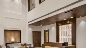 Um hall amplo com balcão de atendimento, área de estar e um painel decorativo.