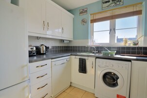 Um frigorífico, uma máquina de lavar louça, utensílios de cozinha 