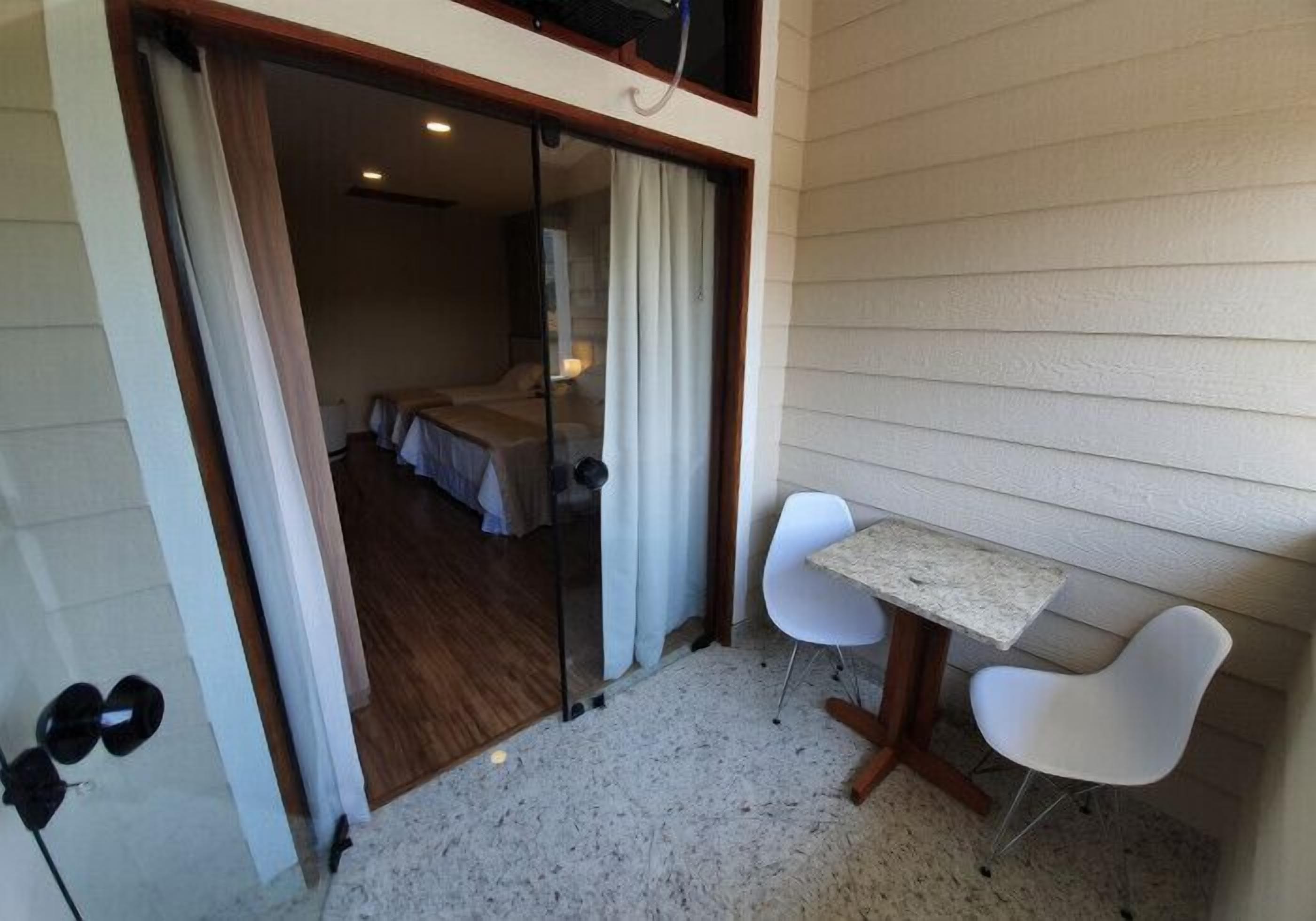 Um quarto pequeno com uma cama, uma mesa e duas cadeiras.