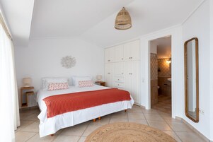 Quarto com cama, mesas de cabeceira, espelho e guarda-roupa.