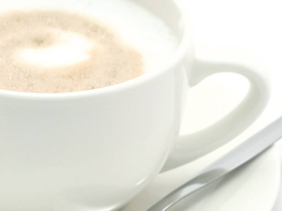 Uma chávena de café branca com uma colher sobre o pires.