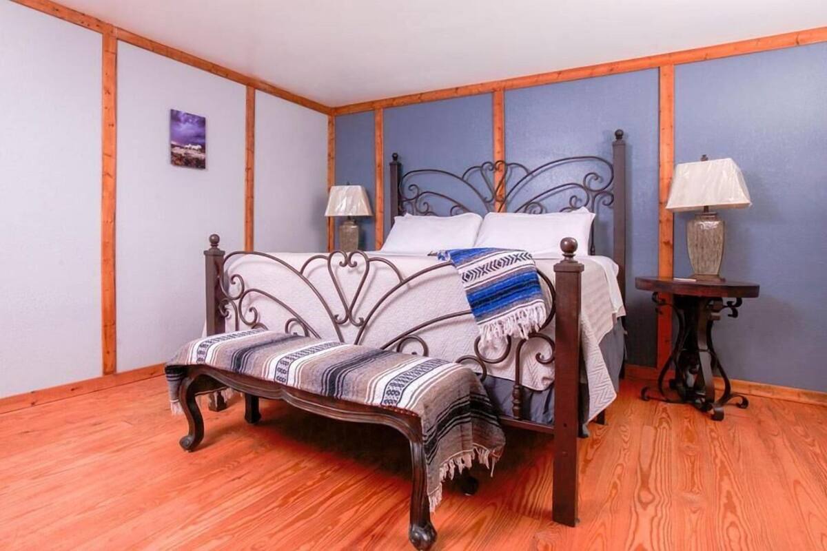 Quarto com cama, duas mesas de cabeceira, um banco e um quadro na parede.