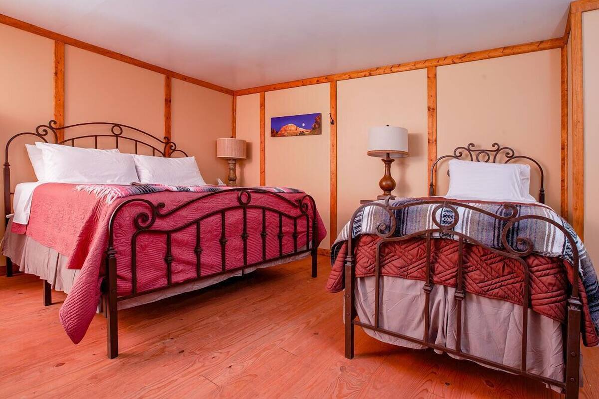 Quarto com duas camas, paredes de madeira e uma pintura na parede.