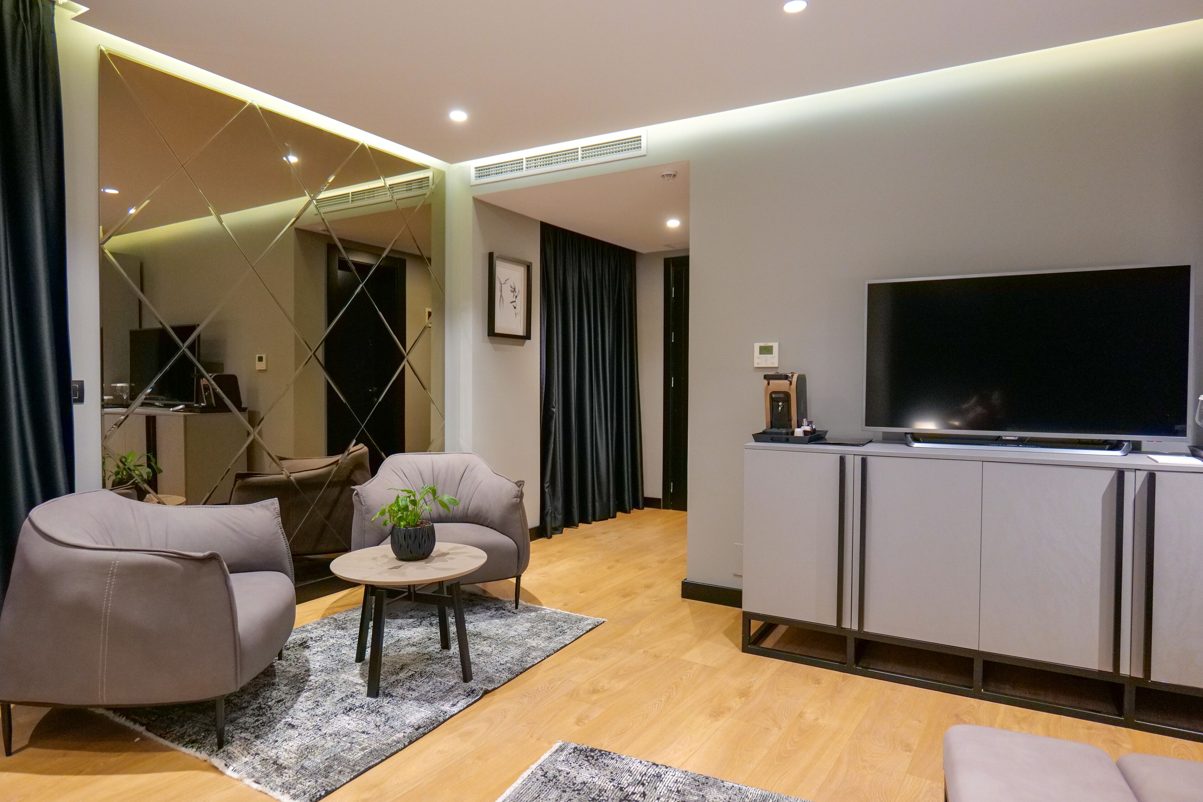 Uma sala de estar moderna com um sofá, uma poltrona e uma mesinha com uma planta.