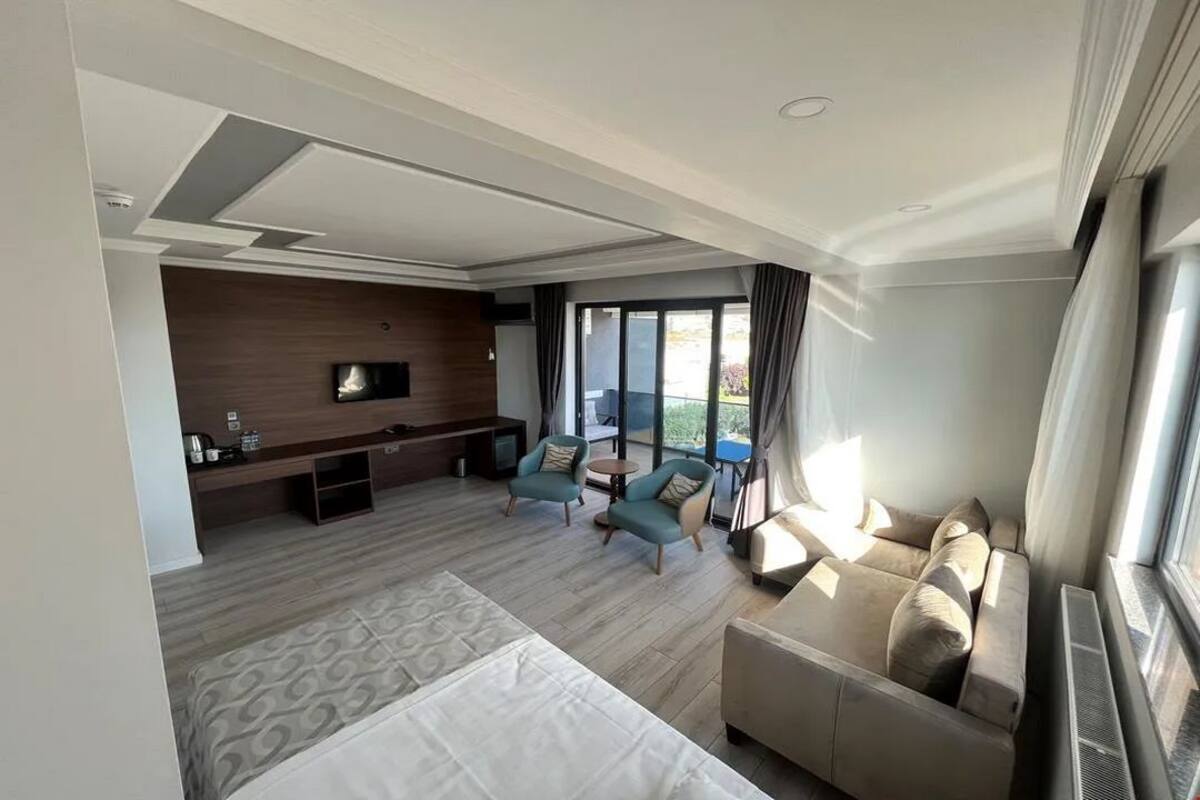 Uma sala de estar moderna com sofá, poltronas, televisão de tela plana e um espaço para refeições.